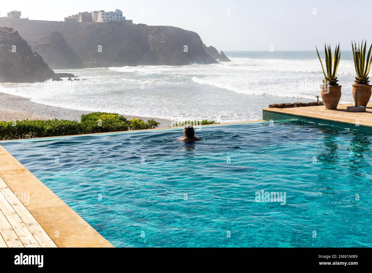 Woman swimming infinity pool by Atlantic Ocean, Hotel auberge Dar ...