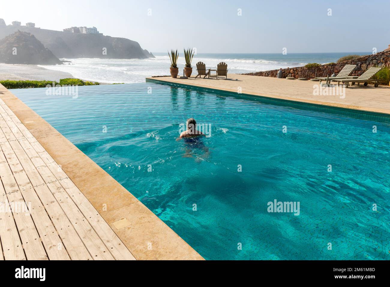 Woman swimming infinity pool by Atlantic Ocean, Hotel auberge Dar ...