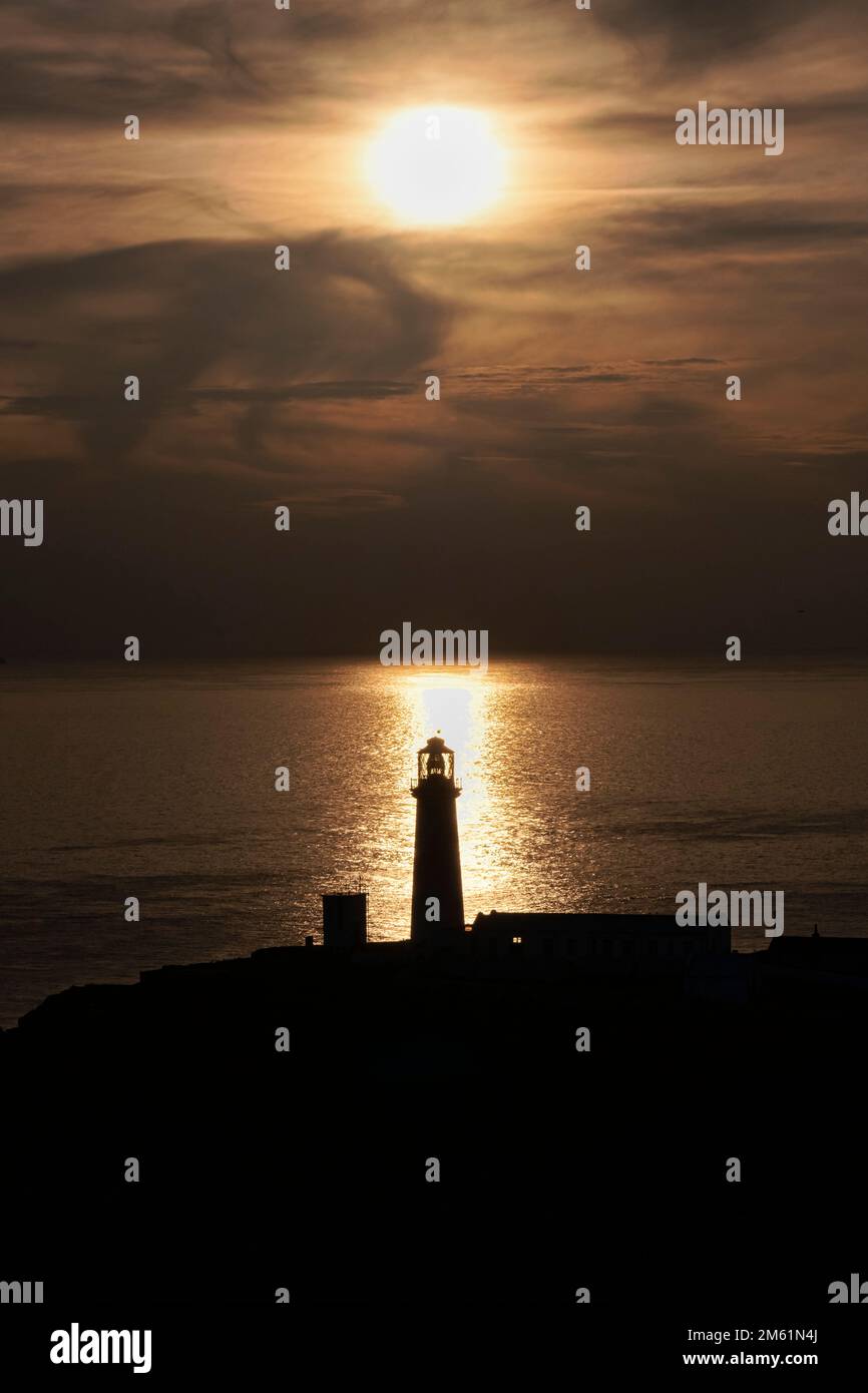 South Stack Lighthouse silhouetted at sunset against the Irish Sea ...