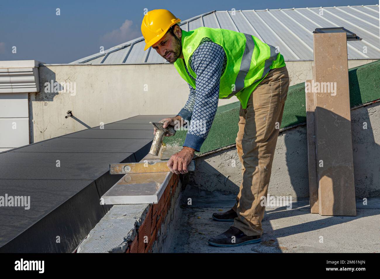 The builder is hitting the marble with a hammer and leveling it with a ...