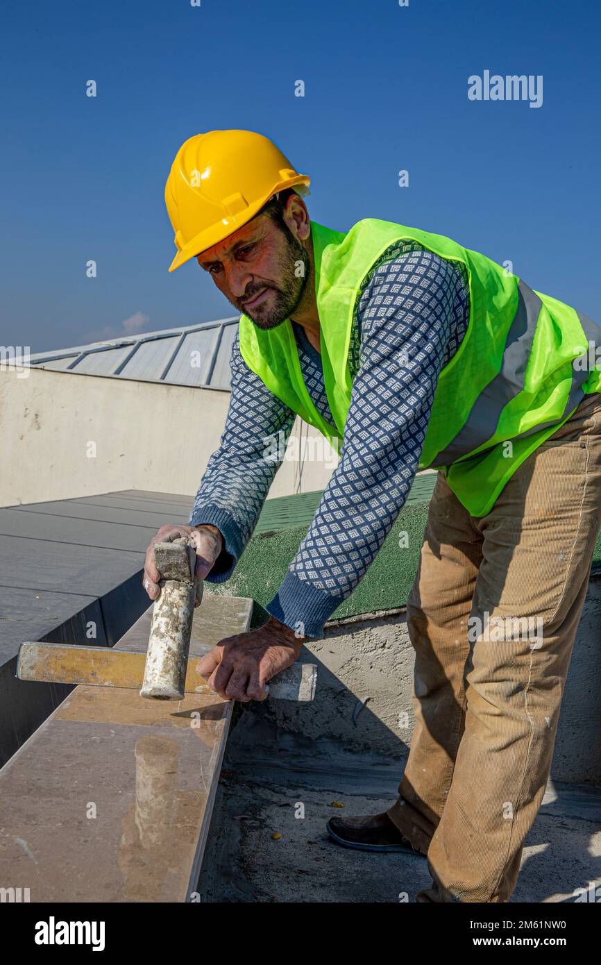 The builder is hitting the marble with a hammer and leveling it with a ...