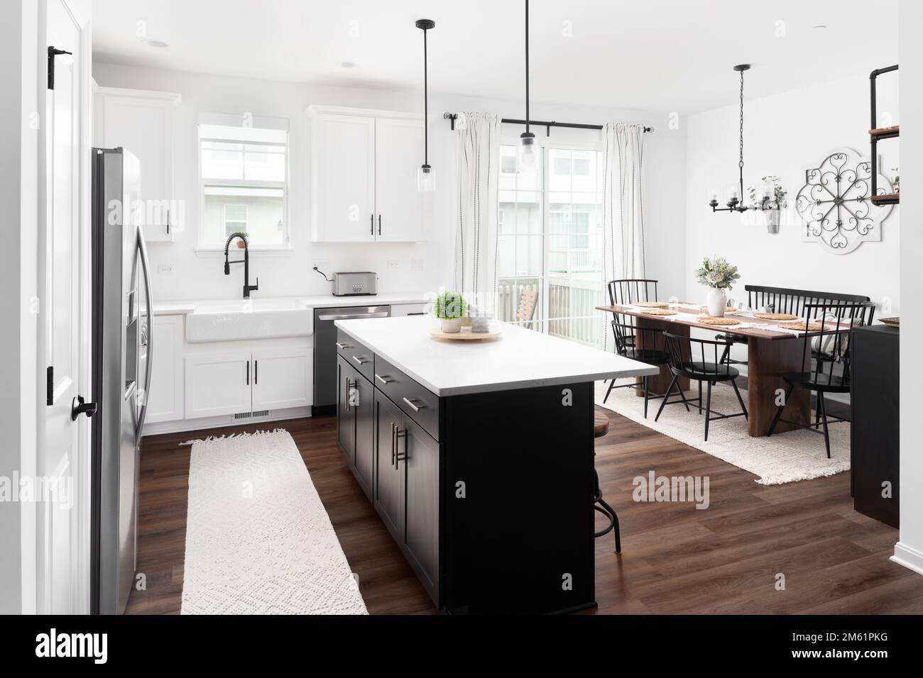 A modern farmhouse kitchen and dining rom with a black island, white ...