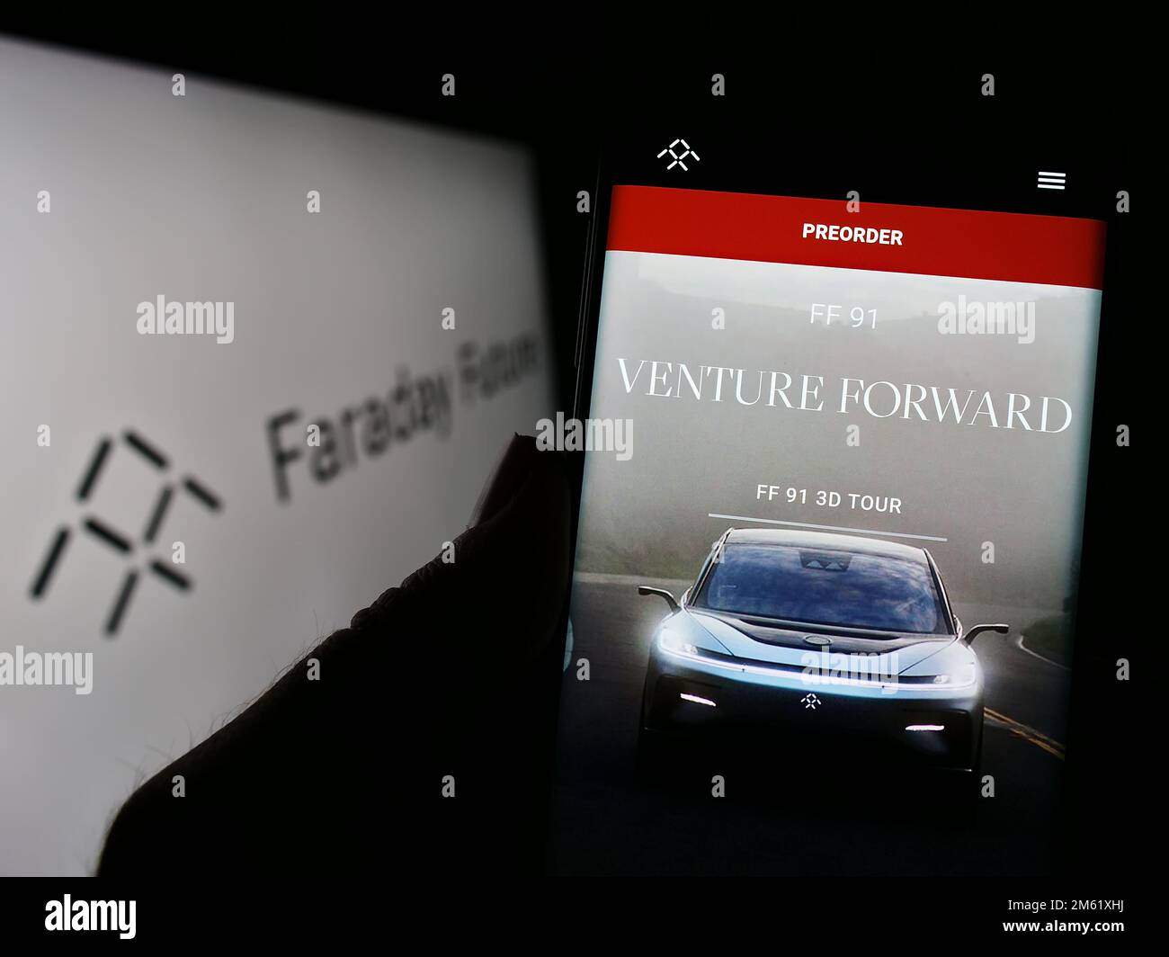 Person holding cellphone with webpage of electric vehicle company ...