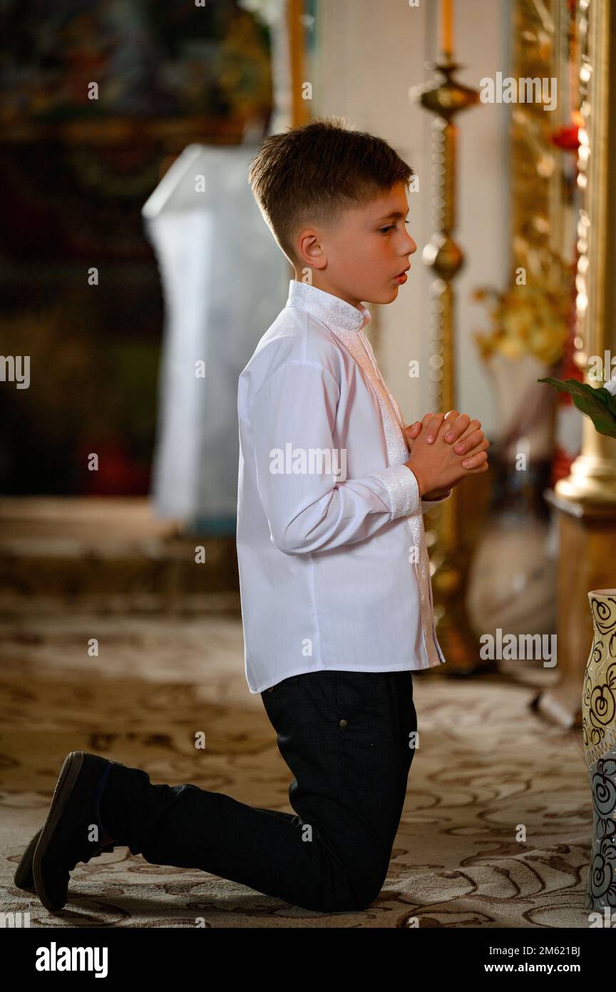 A boy is kneeling in prayer to God, children's prayer in the church ...