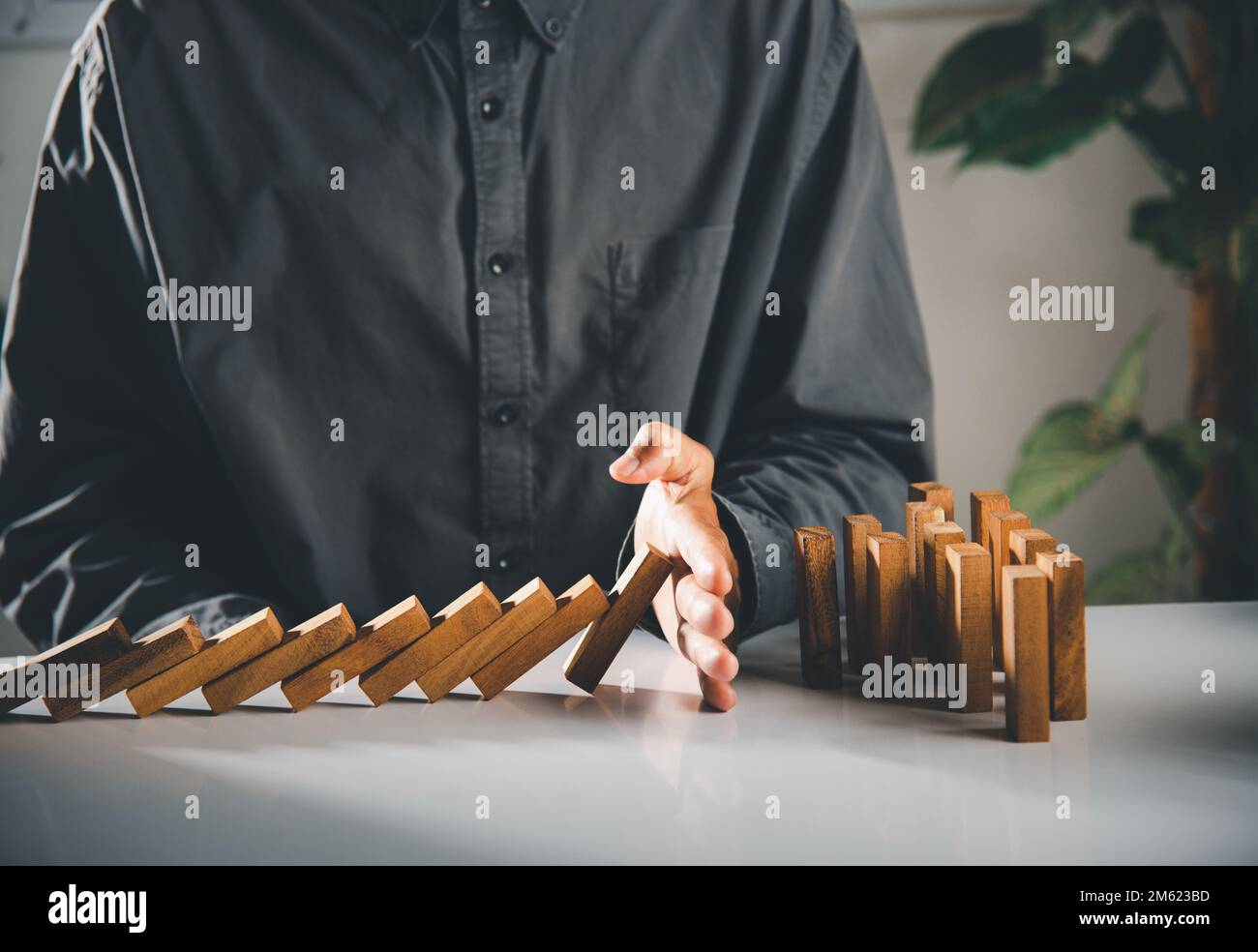 Man hand blocks wood block from many row falling wooden block like ...