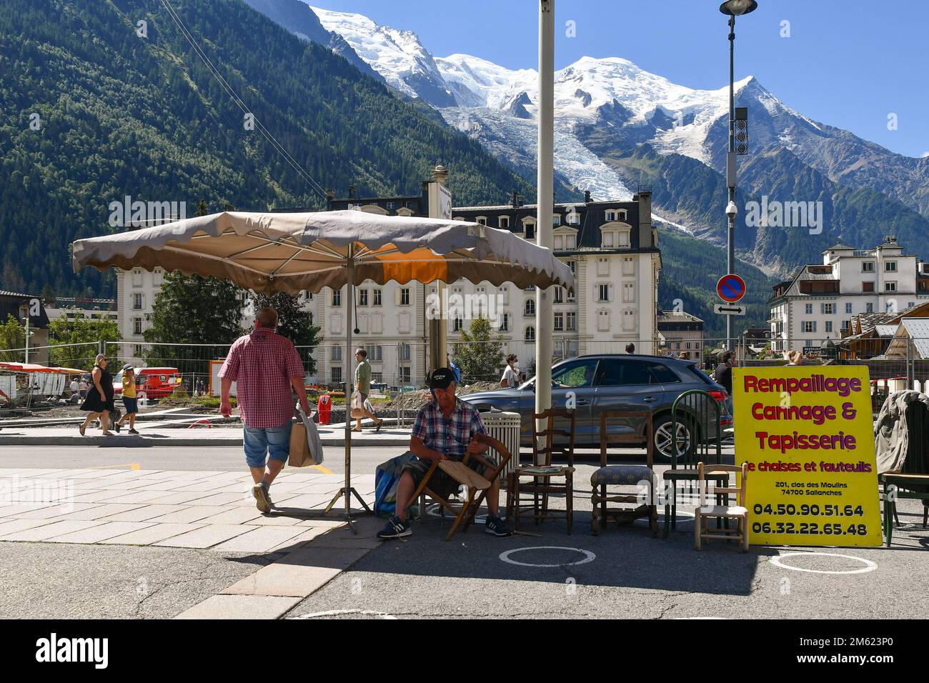 An artisan upholsterer fixing a chair at the street market of Chamonix ...