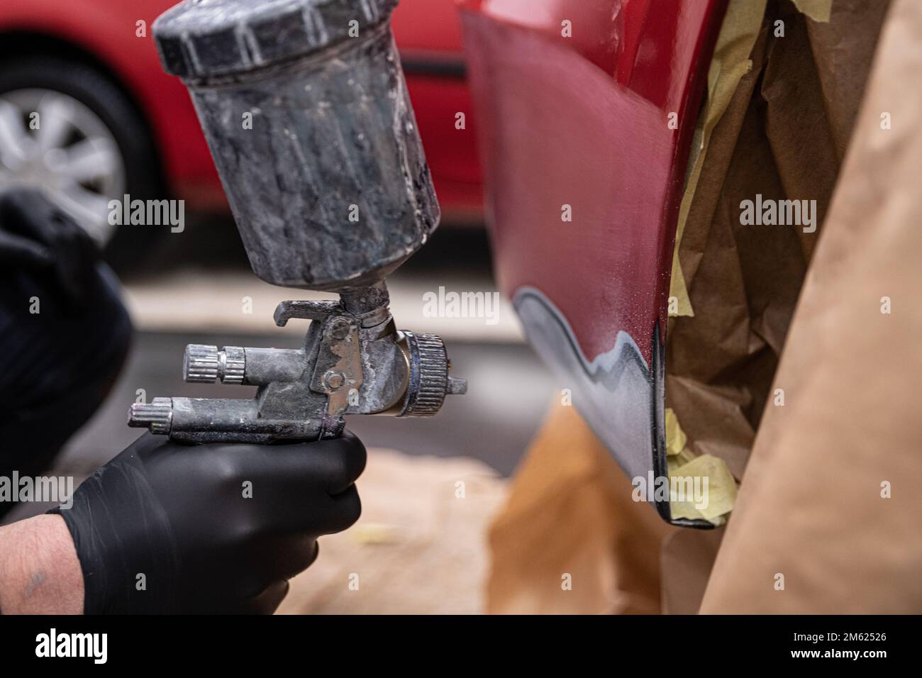 Painter paints with primer paint damage on the bumper of a red car ...