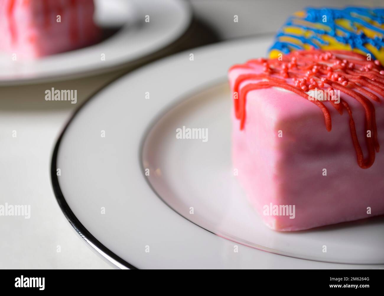 Pink and yellow cake bites on white china dishes Stock Photo - Alamy