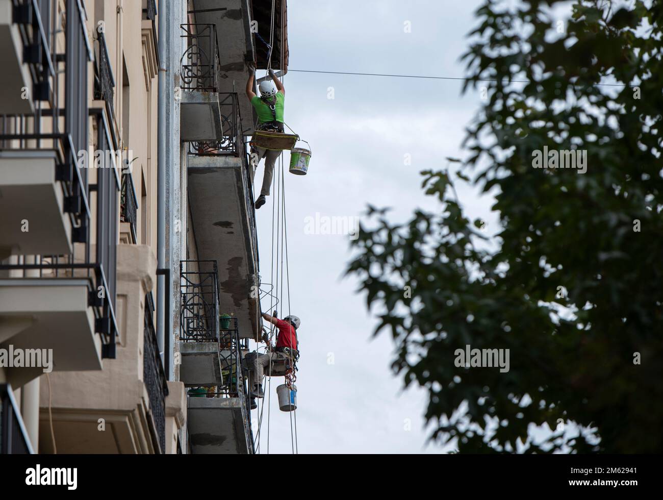 painters working on facade hanging from ropes Stock Photo - Alamy