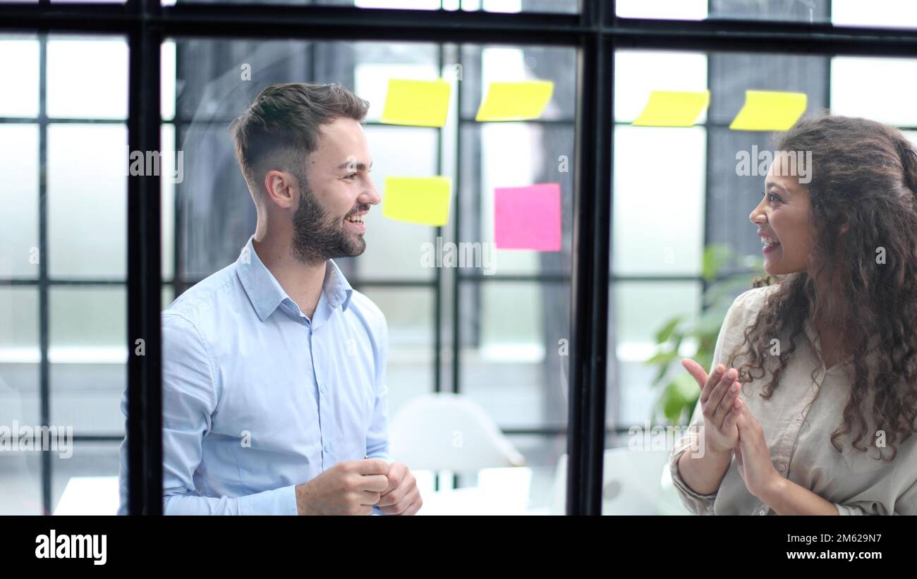 Businessman writing sticking adhesive notes on glass wall in office and ...
