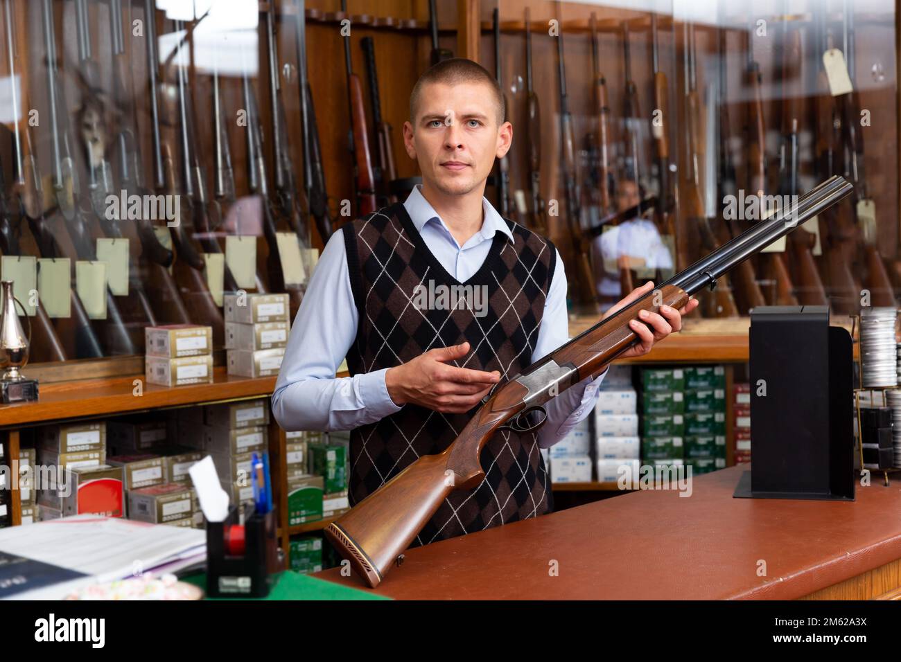 Gun shop salesman showing double barreled hunting rifle Stock Photo - Alamy