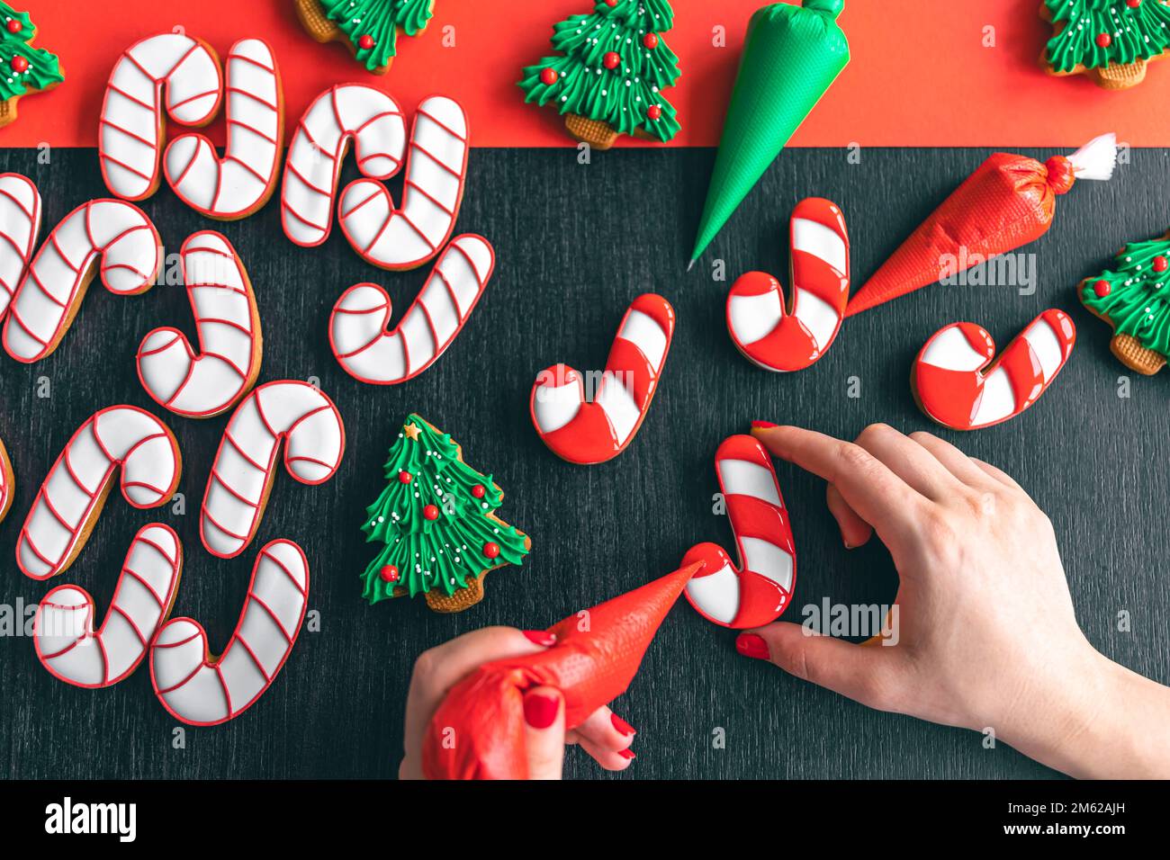 A woman covers with icing Christmas gingerbread in the form of a candy ...