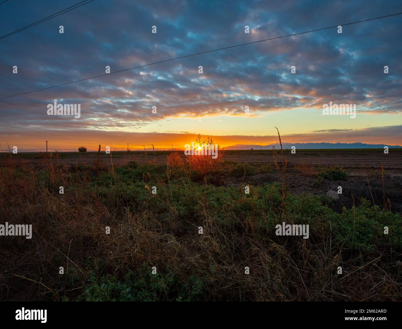 A bright winter sunset in the Arizona desert casts multiple vibrant ...