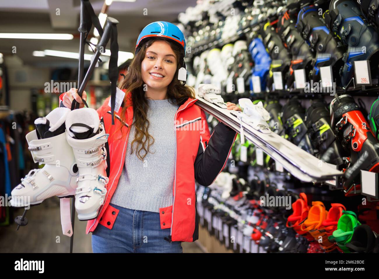Smiling young girl chose skis, shelm and boots Stock Photo - Alamy