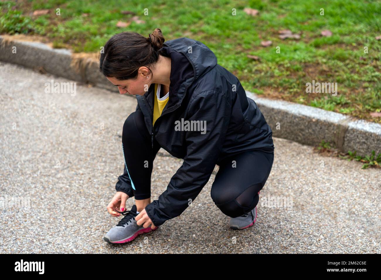From above full body of female jogger in black windbreaker and sneakers ...