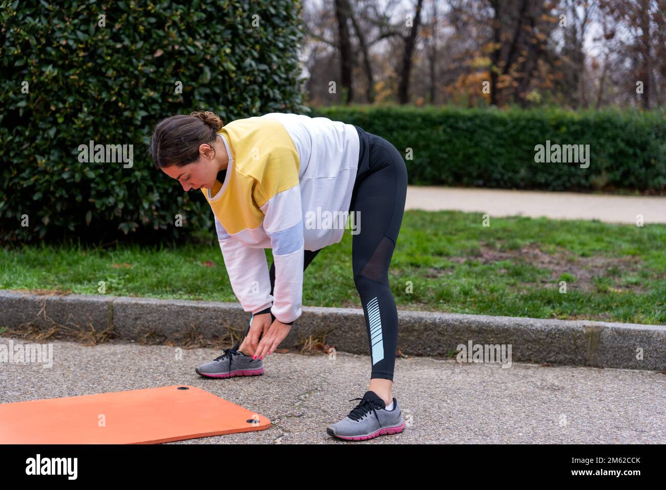 Side view full body of young sporty female in activewear doing forward ...