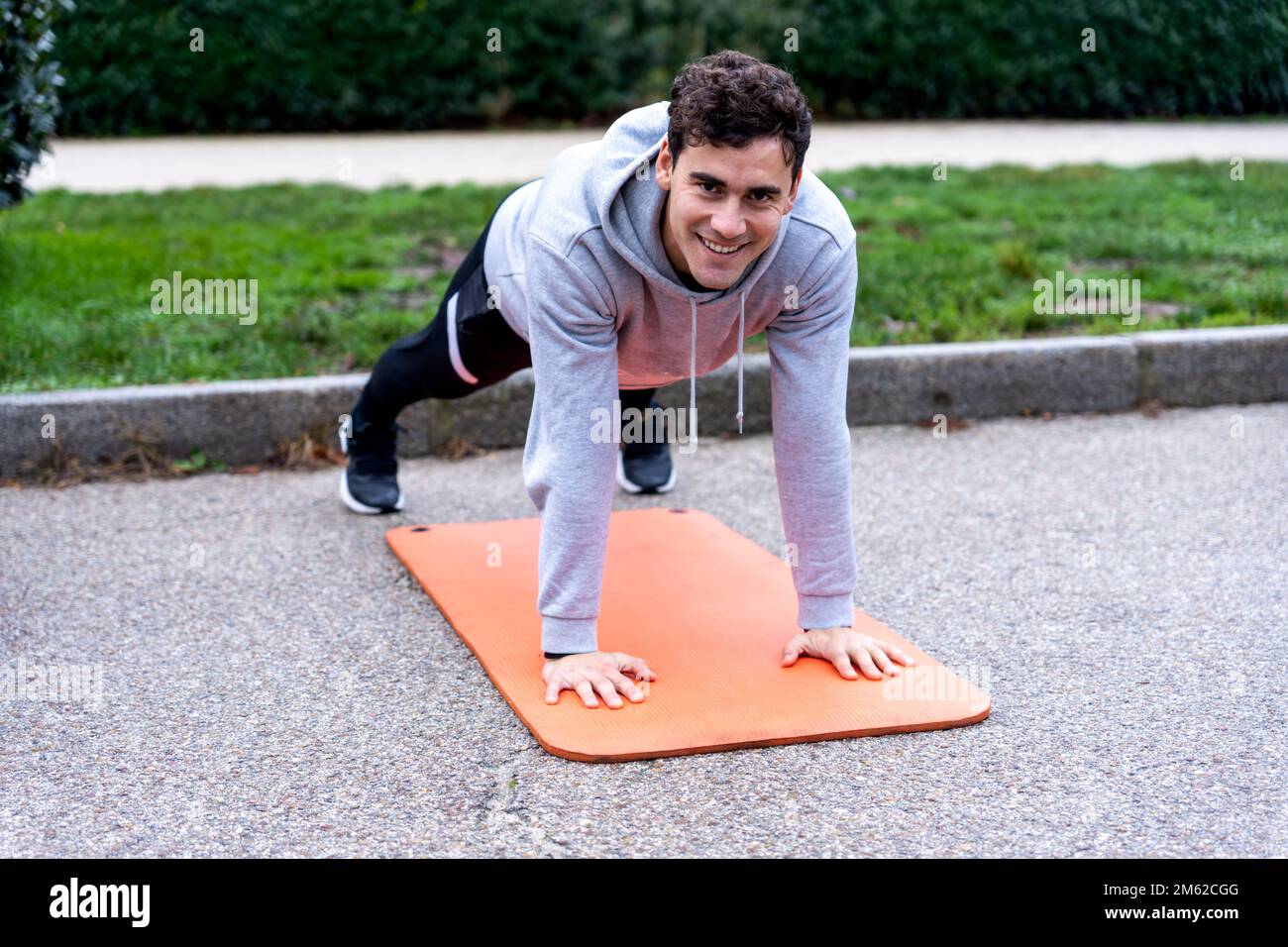 Full body of young smiling male athlete in sportswear doing plank ...