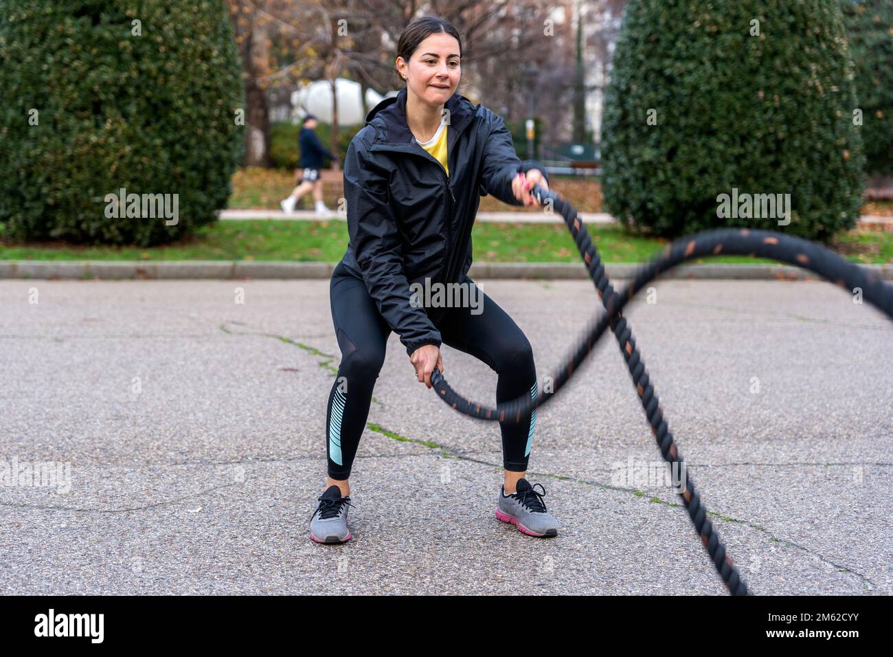 Full body of focused young female athlete in windbreaker and leggings ...