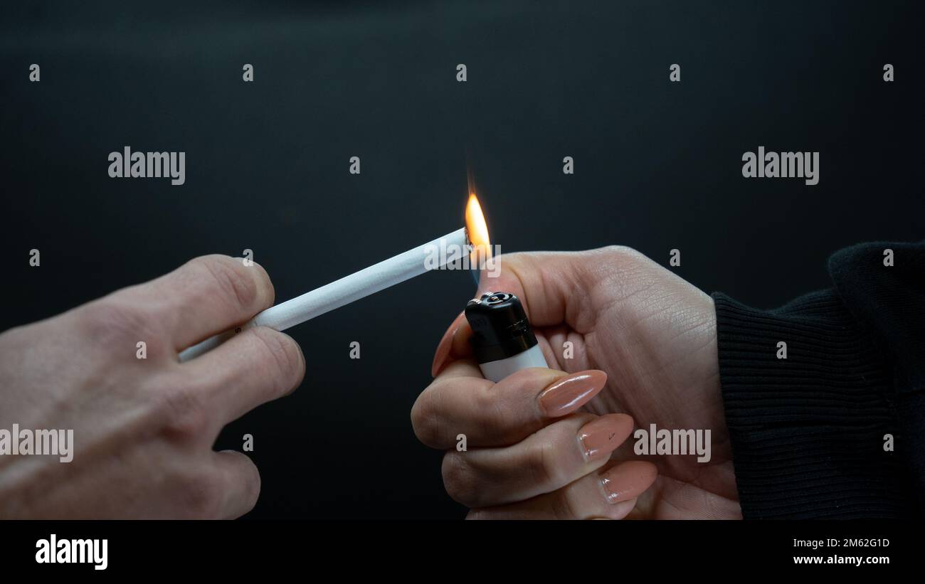 man holding a cigarette on a black background. burning cigarette with ...