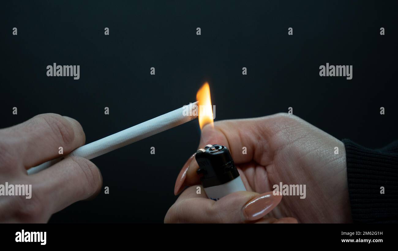 man holding a cigarette on a black background. burning cigarette with ...