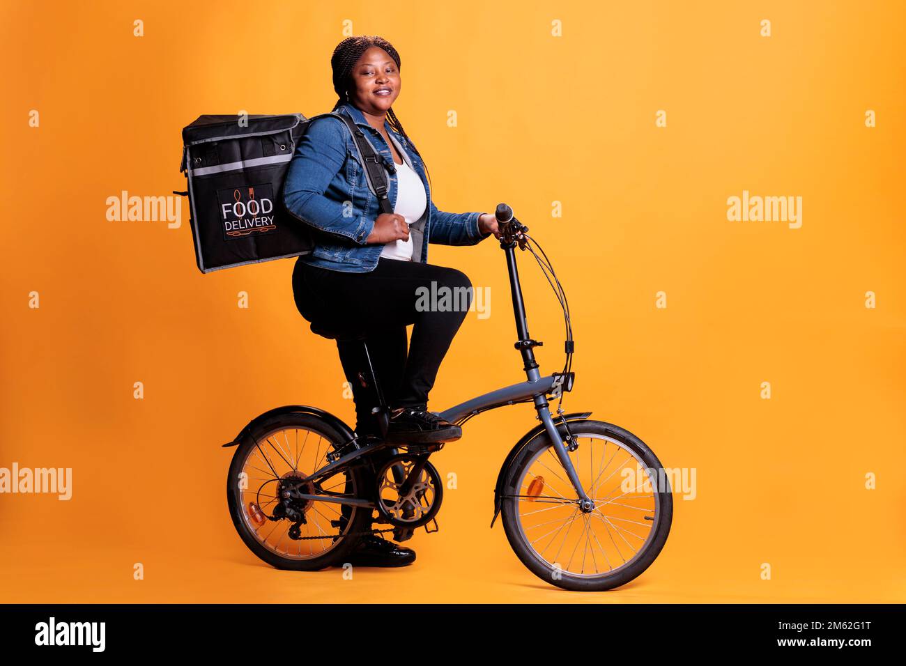 Portrait of fast food delivery worker riding bike during lunch time ...