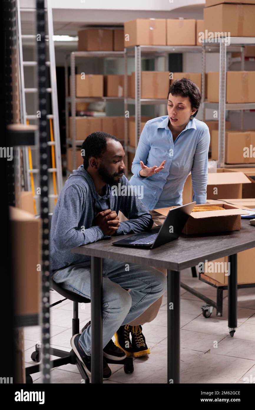 Multi ethnic workers analyzing client delivery data on laptop computer ...