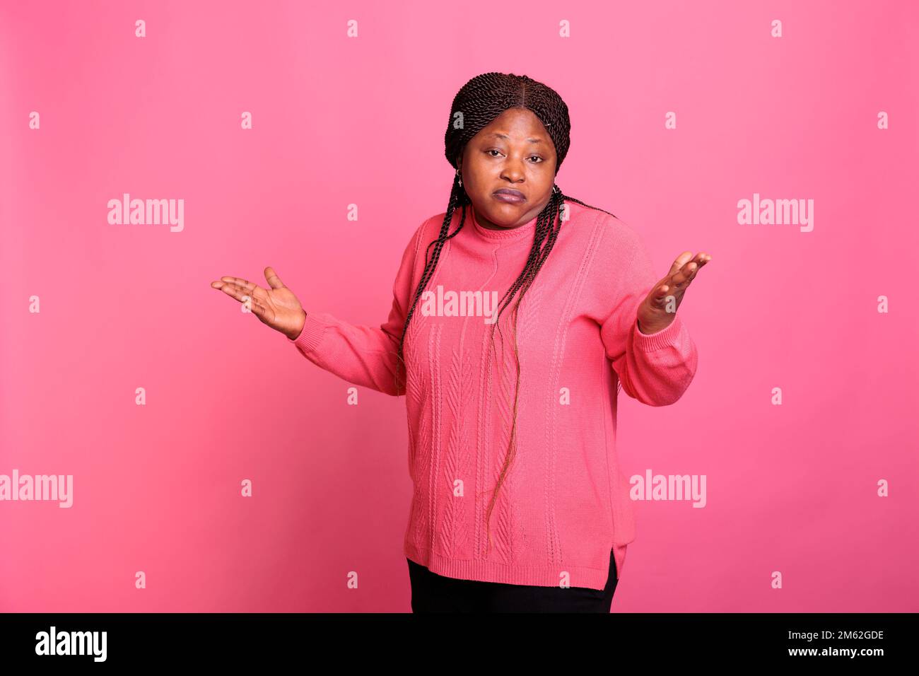 Portrait of doubtful african american woman posing on pink background ...