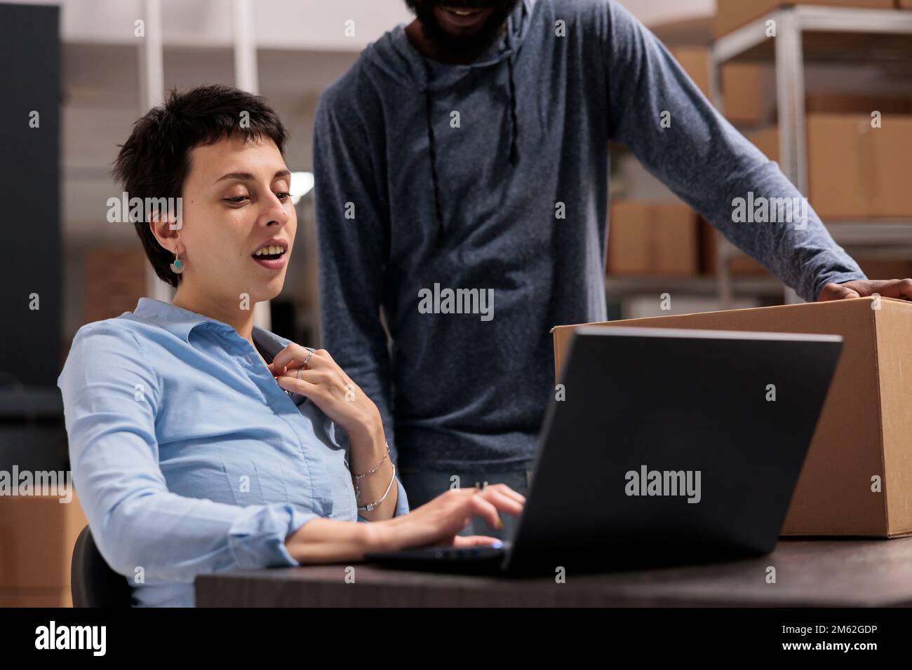 Warehouse employees looking at transportation logistics on laptop ...