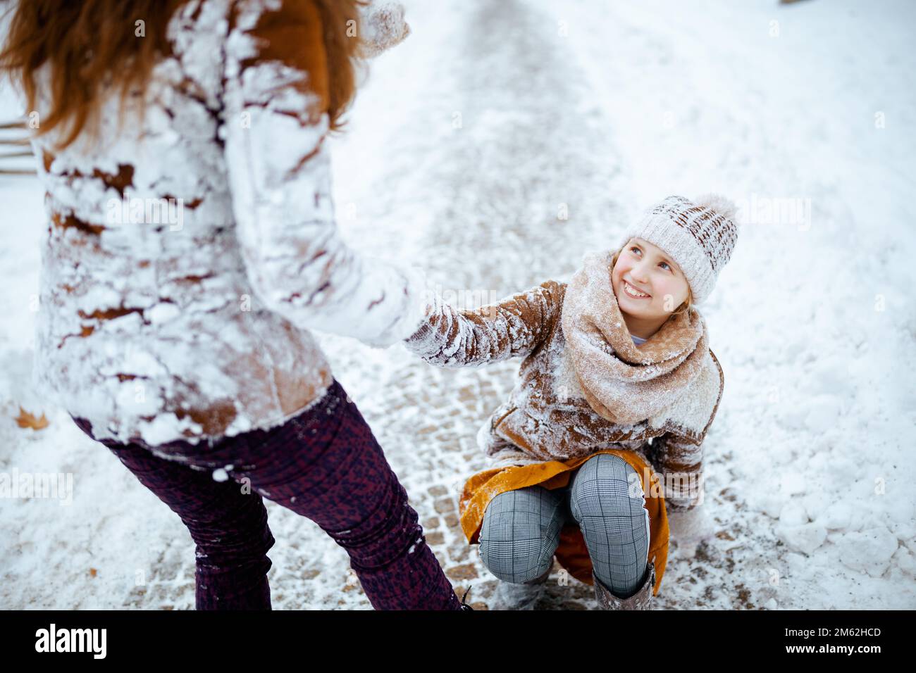 mother helping daughter getting up after falling outdoors in the city ...