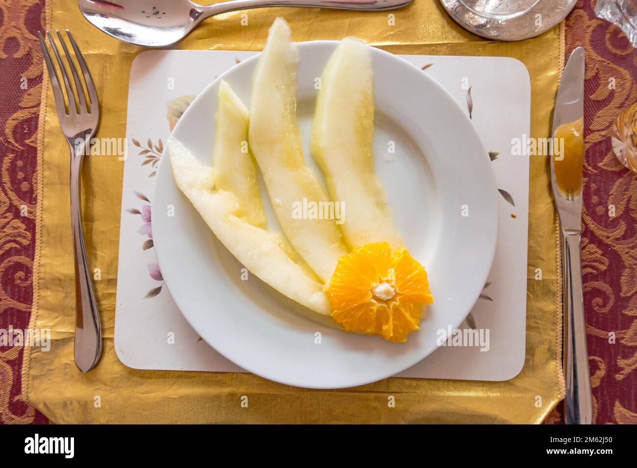 Slices of honeydew melon garnished with a slice of orange served as a ...