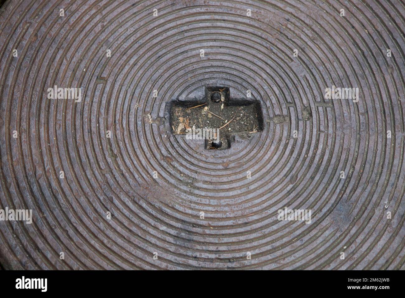 Sidewalk, metallic utility cap with concentric circles, serving as a ...