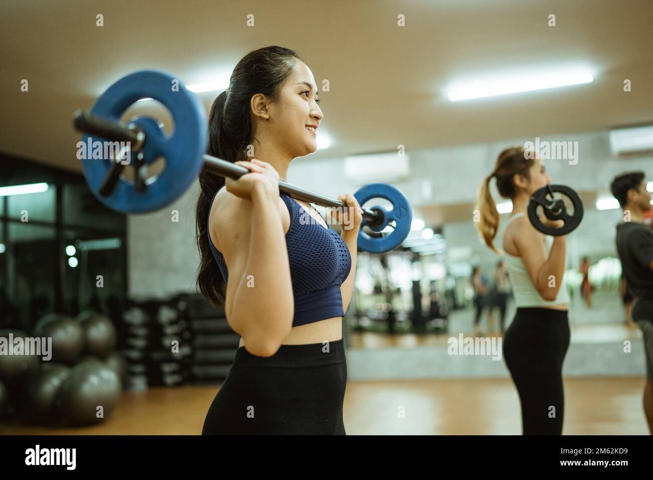 young asian woman lifting barbell in front of chest during exercise in ...