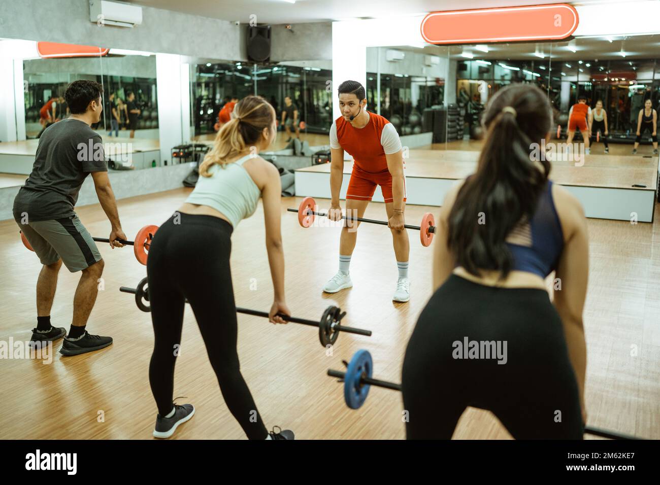 group of young sporty people lifting barbells while bending Stock Photo ...