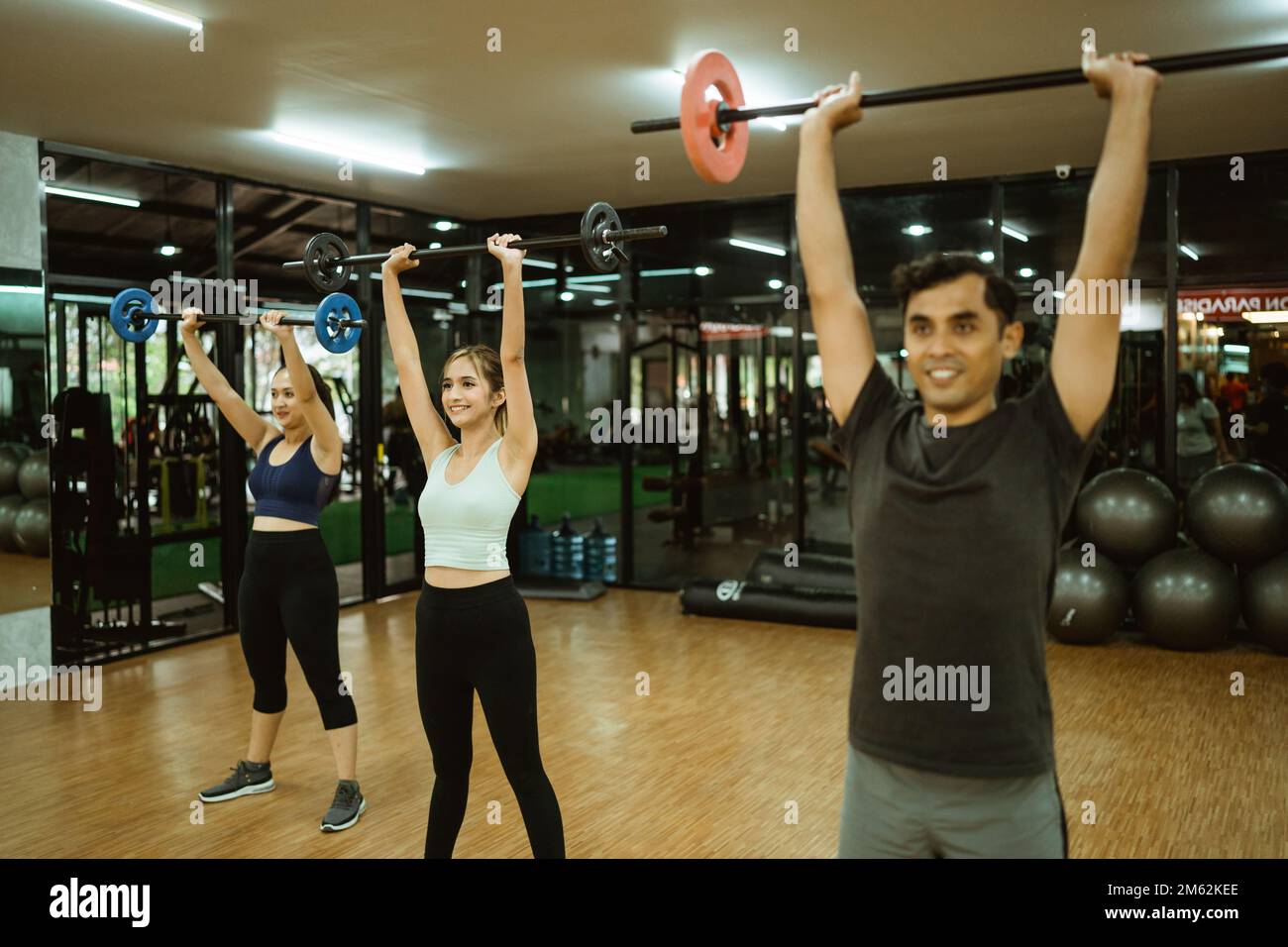 group of sporty asian people lifting barbells up during exercise Stock ...