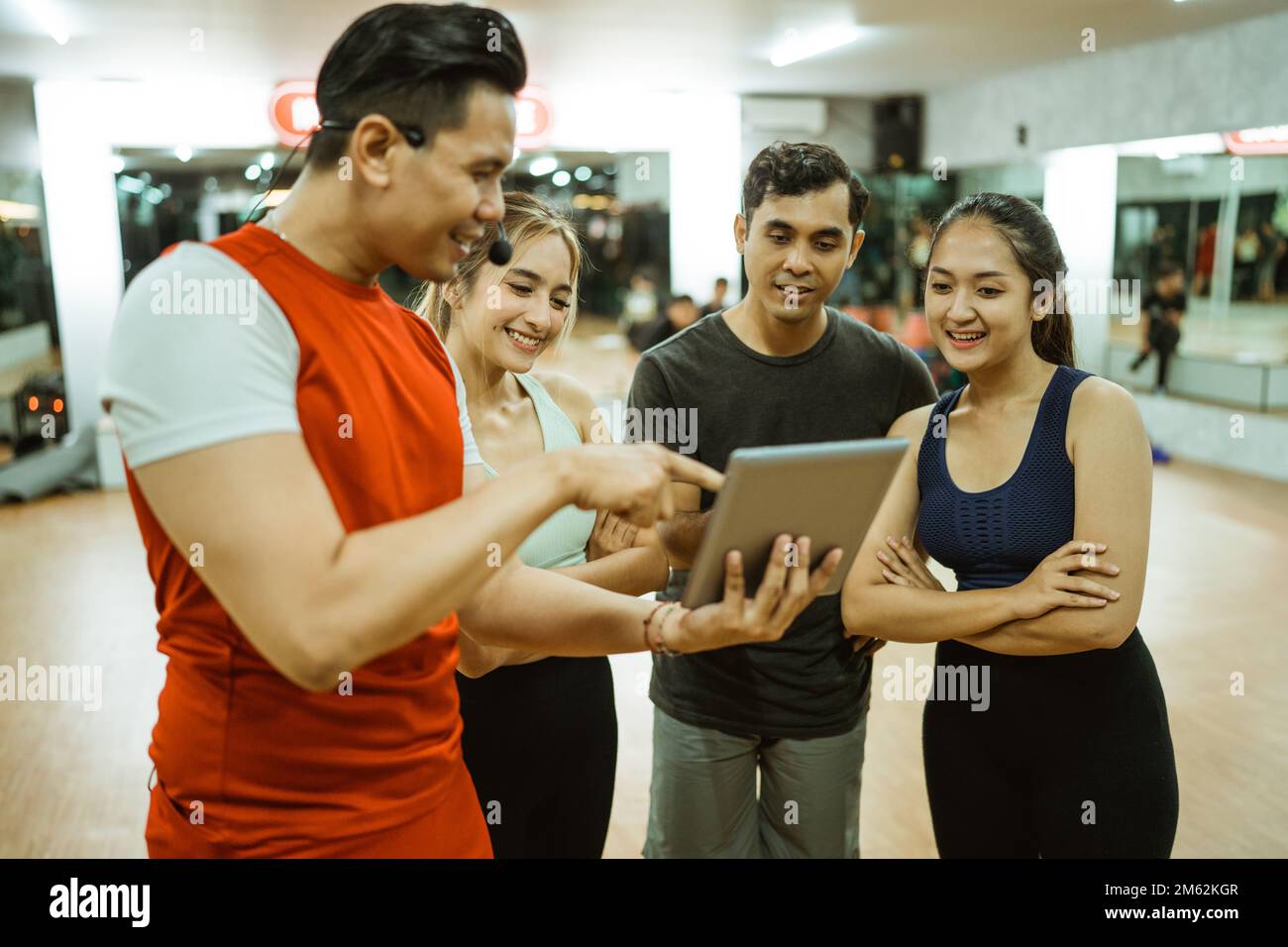 male instructor showing tablet to young sporty people in gym Stock ...