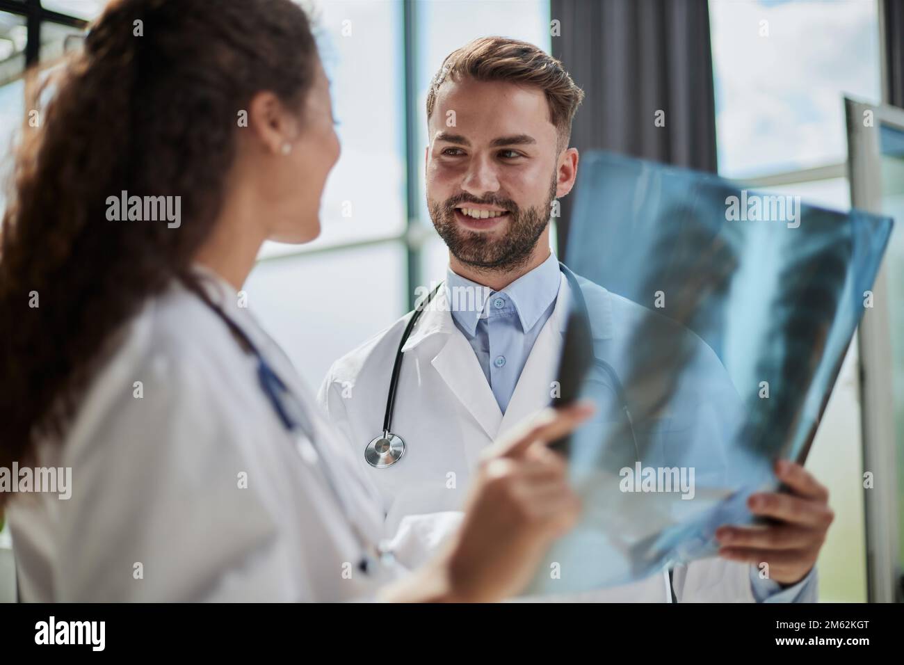 Young serious competent male doctor looking at X-ray at doctor's office ...