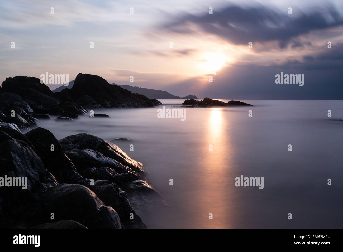The rocks on Kamala Beach at sunset. Long exposure gives a silky smooth ...