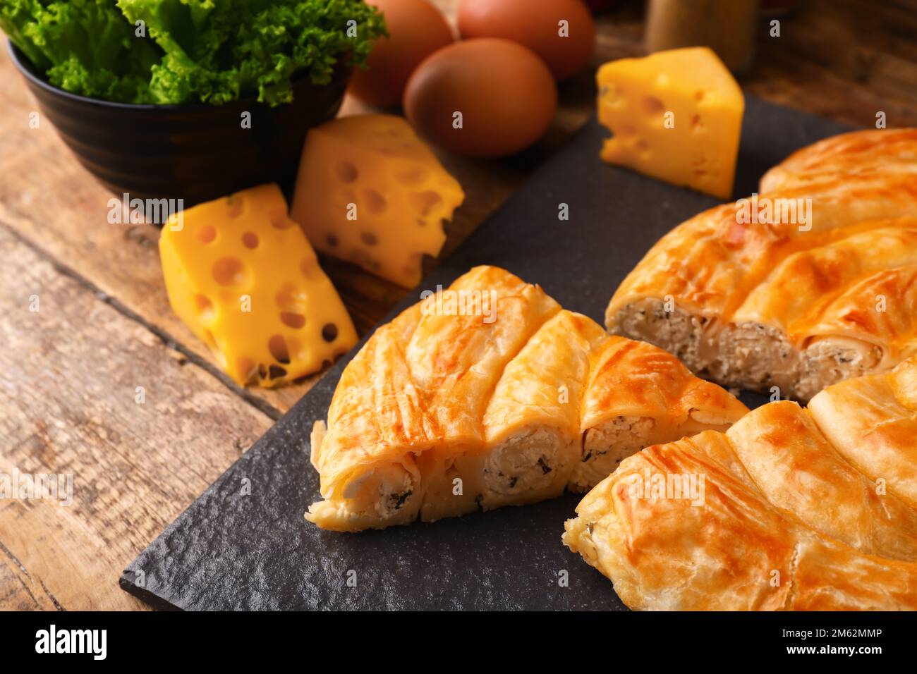 Slate board with delicious cheese pie and ingredients on wooden ...