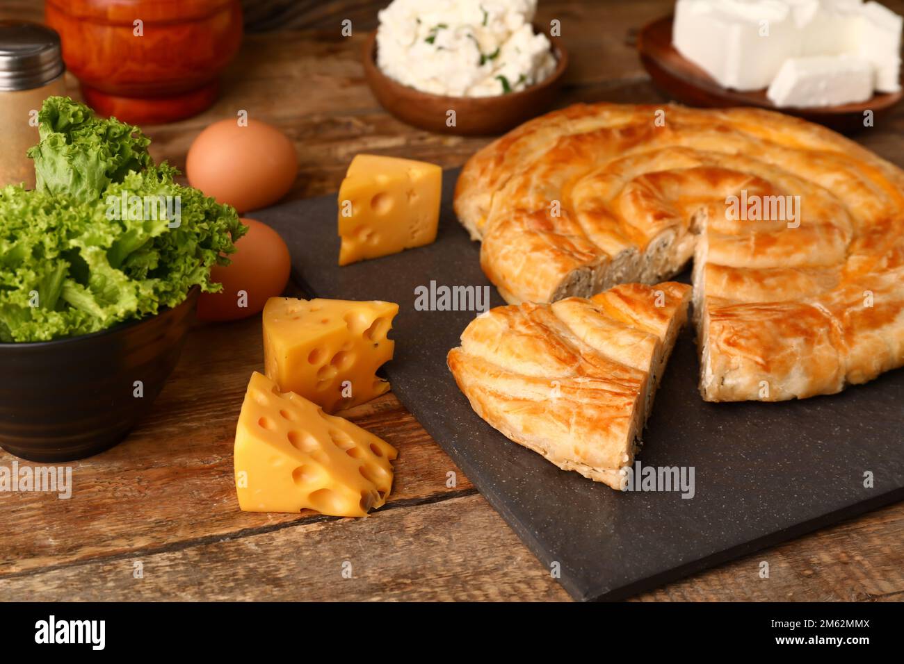 Slate board with delicious cheese pie and ingredients on wooden ...
