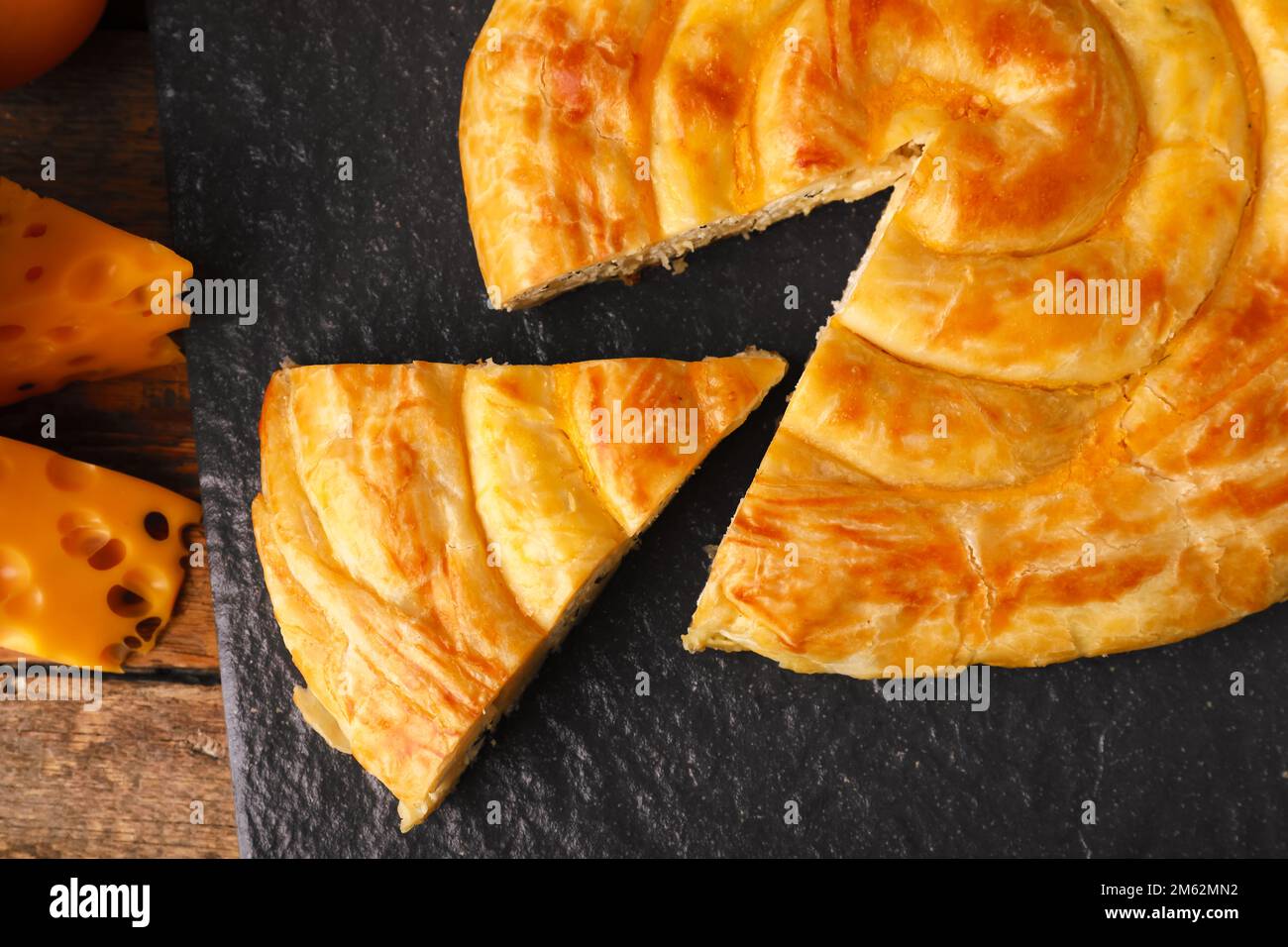 Slate board with delicious cheese pie and ingredients on wooden ...