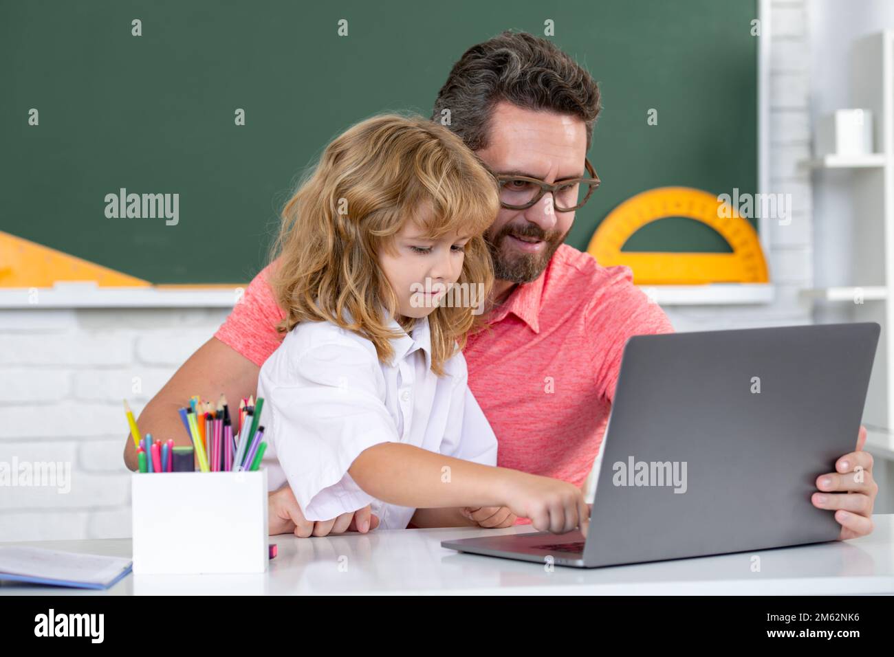 School teacher and child pupil learning at laptop computer, studying ...