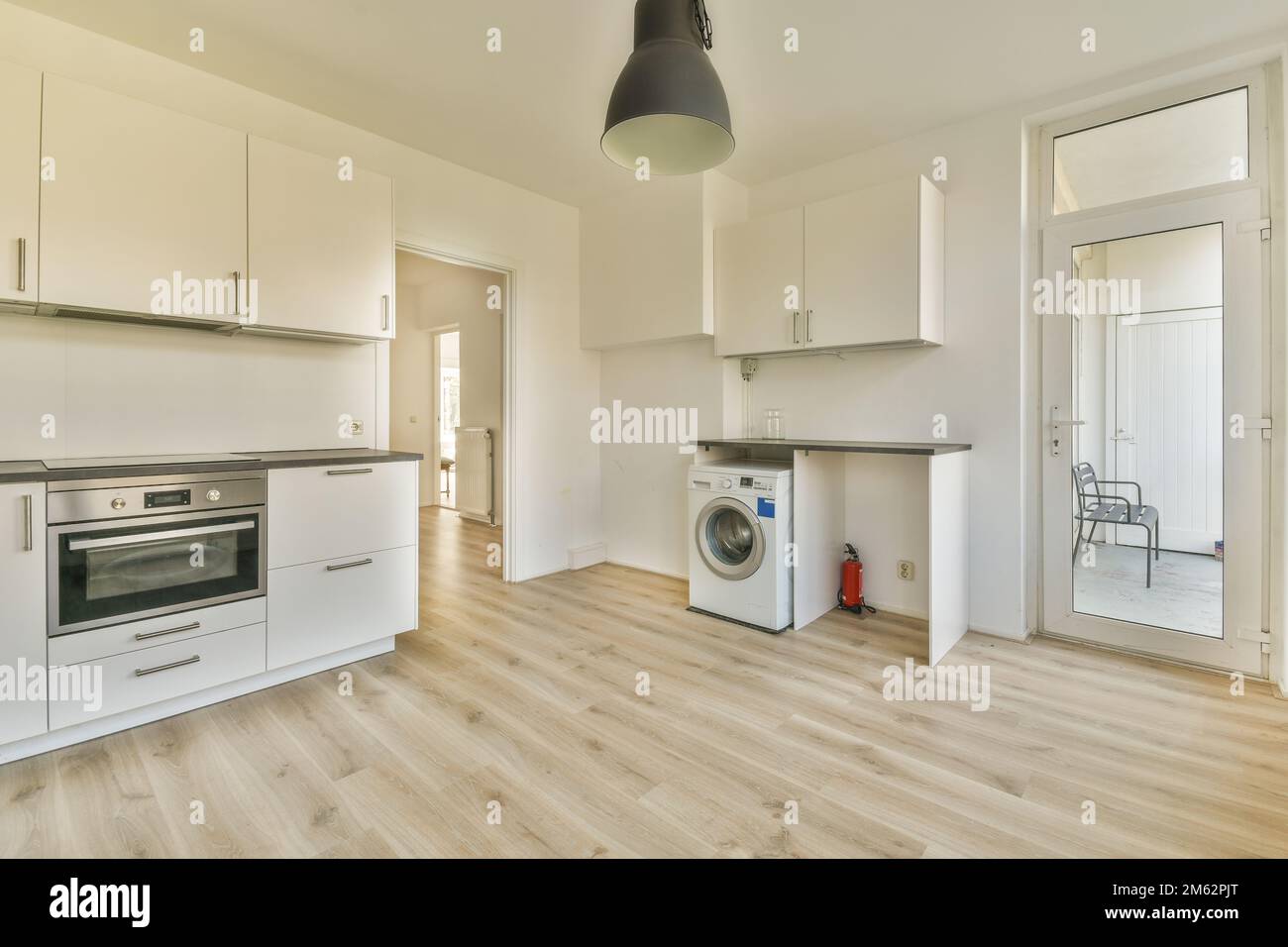 an empty kitchen with wood flooring and white cupboards on either side ...
