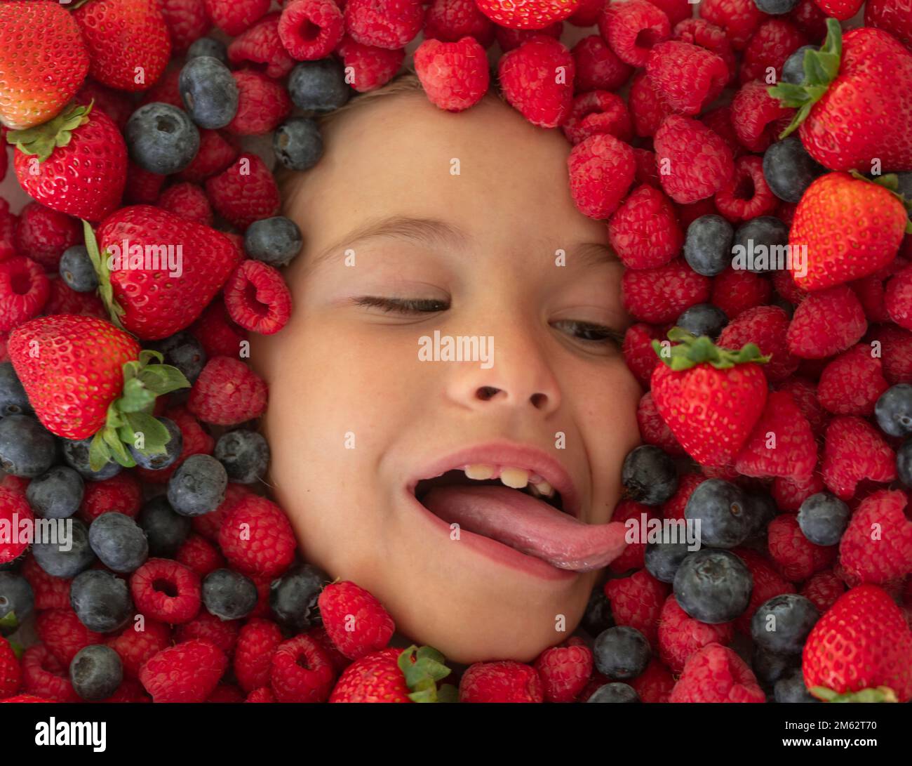 Funny fruits. Kids face with close-up berry. Berries mix of strawberry ...