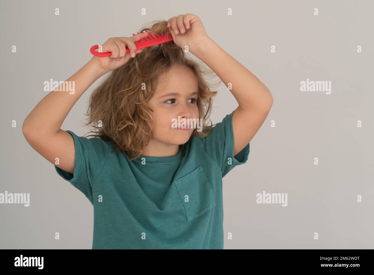 Cute child with curly blonde hair holding comb hairbrush for combing ...