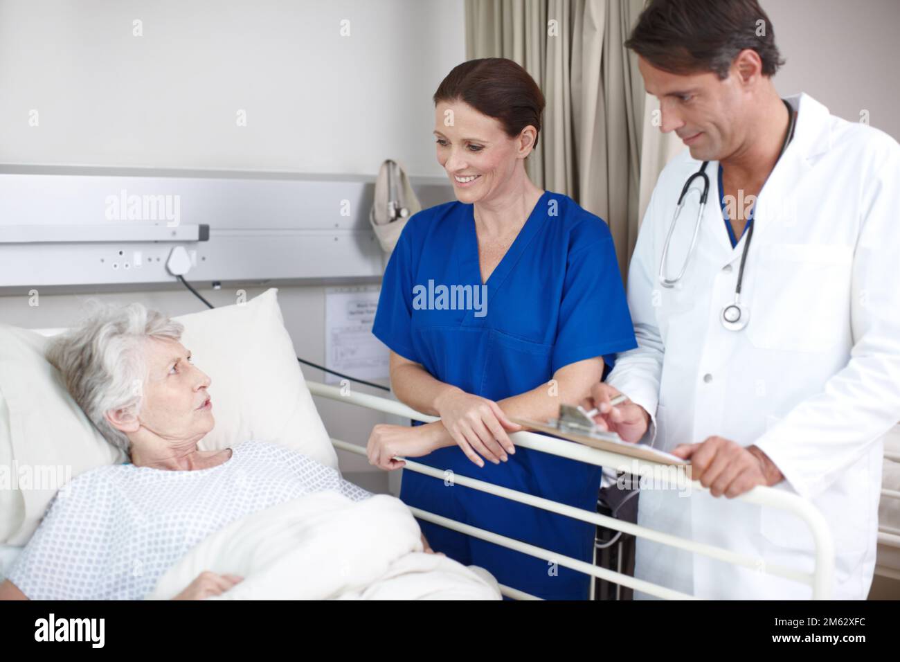 Your recovery is going well. A doctor and his nurse standing over their ...