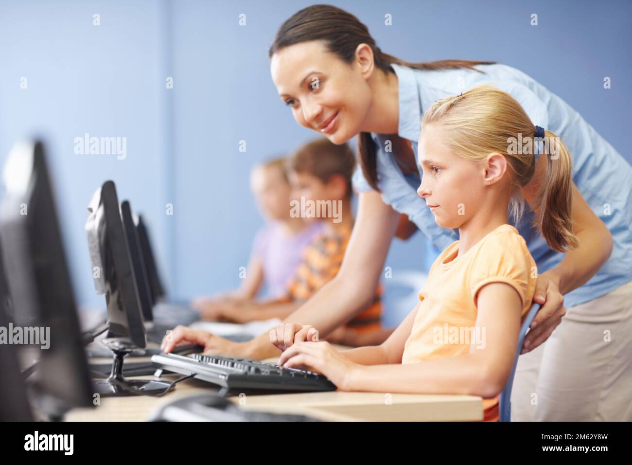 Giving advice in computer class. An beautiful young teacher assisting ...
