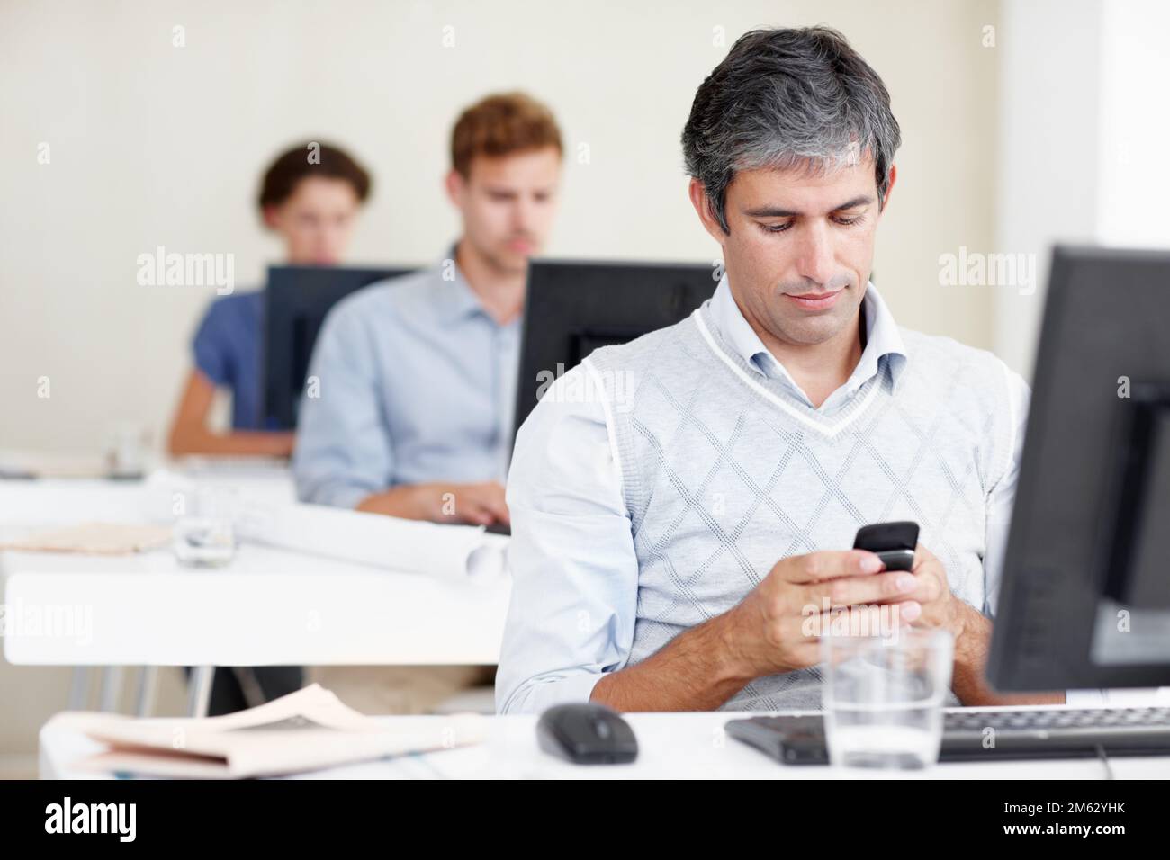 Getting distracted at work. an office worker sending a text message ...