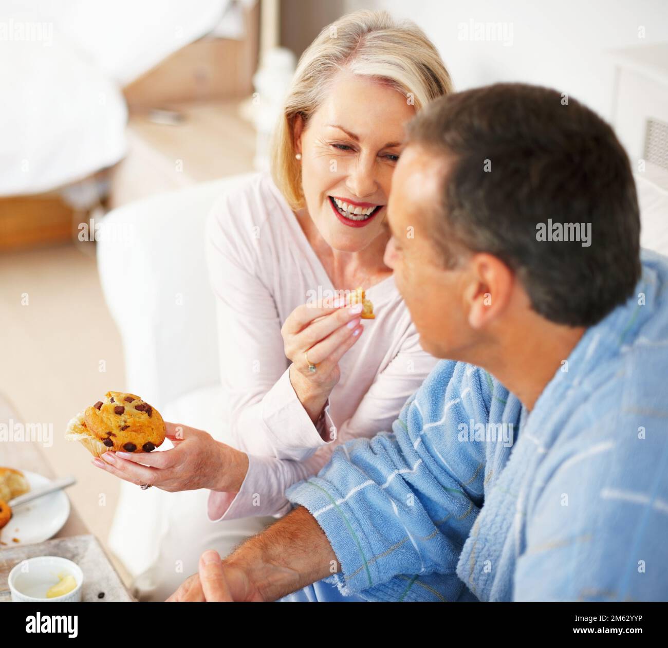 Cheerful mature woman feeding Muffin to husband. Portrait of a cheerful ...