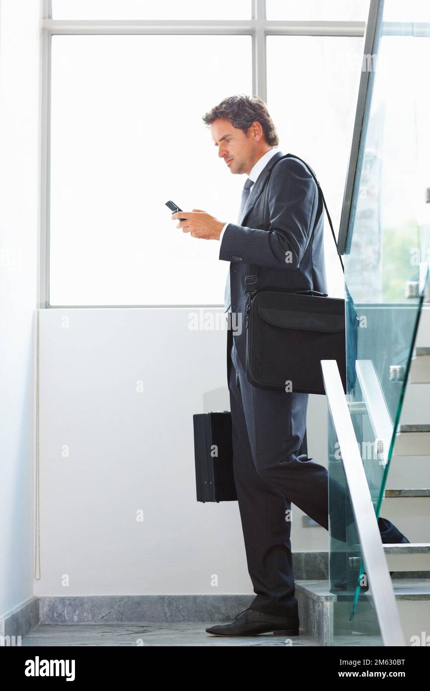 Business man using cellphone on stairs. Full length of handsome middle ...