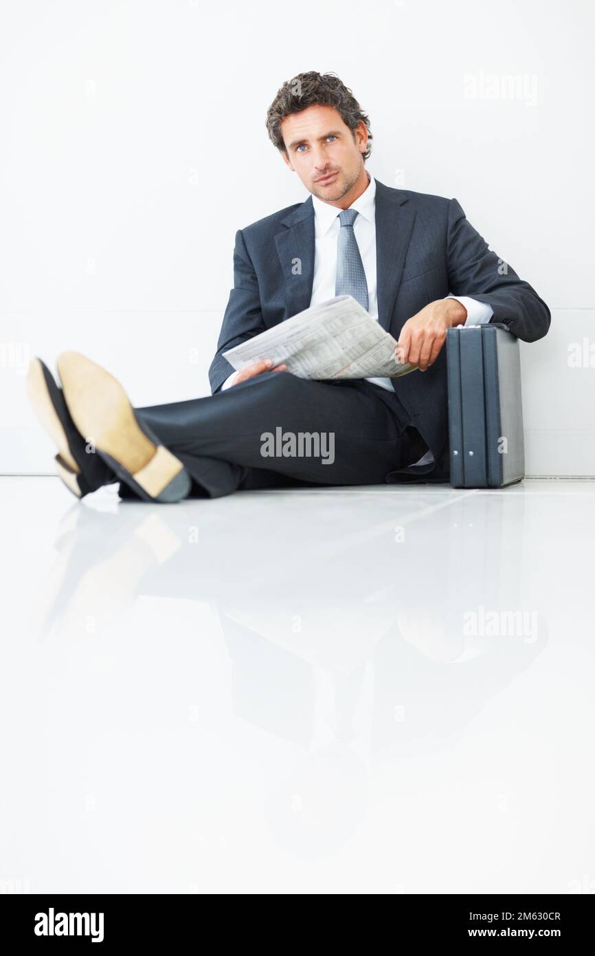 Handsome business man sitting against wall with newspaper. Portrait of ...